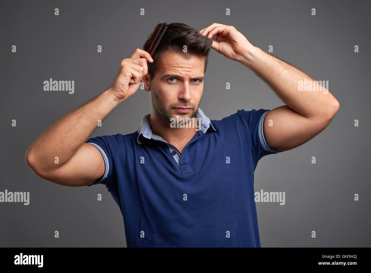 A serious handsome young man combing his hair Stock Photo - Alamy