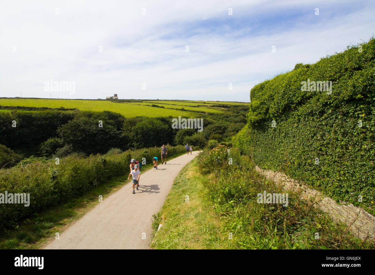 Tourists visiting Tintagel castle walk & run on the steep hilly path ...