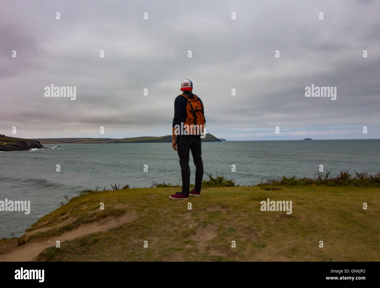 Man in baseball cap stands overlooking the ocean in Cornwall Stock ...
