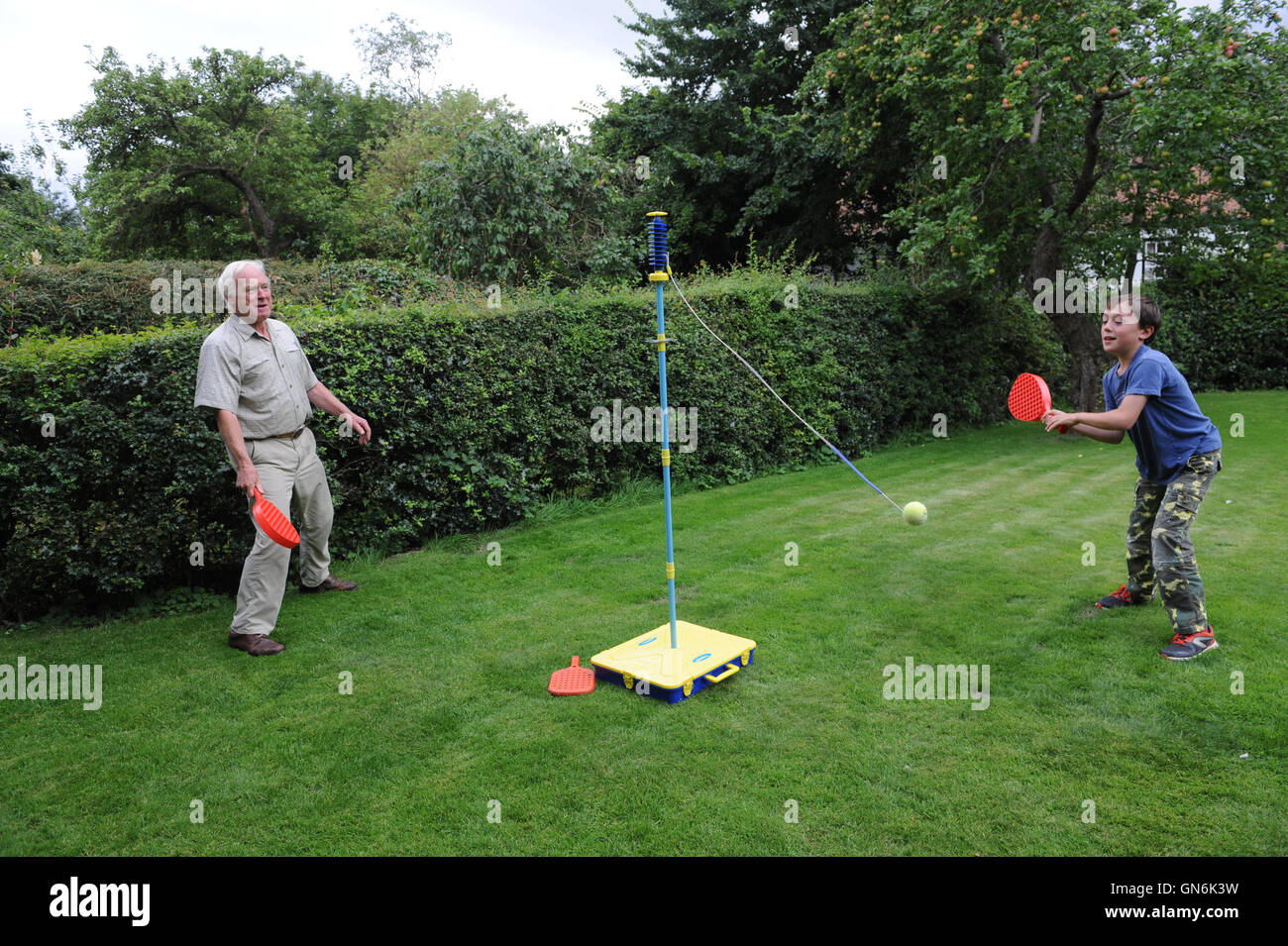 Grandfather playing Swingball with his Grandson in the garden Stock ...