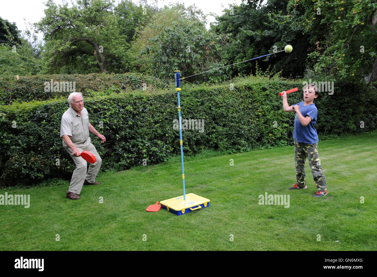 Grandfather playing Swingball with his Grandson in the garden Stock ...