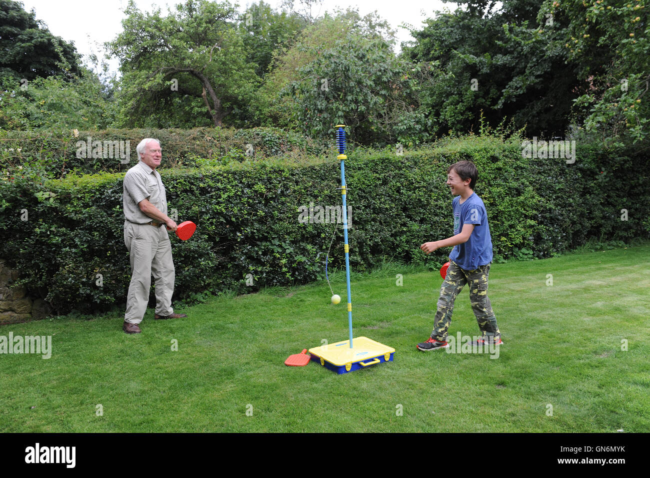 Grandfather playing Swingball with his Grandson in the garden Stock ...