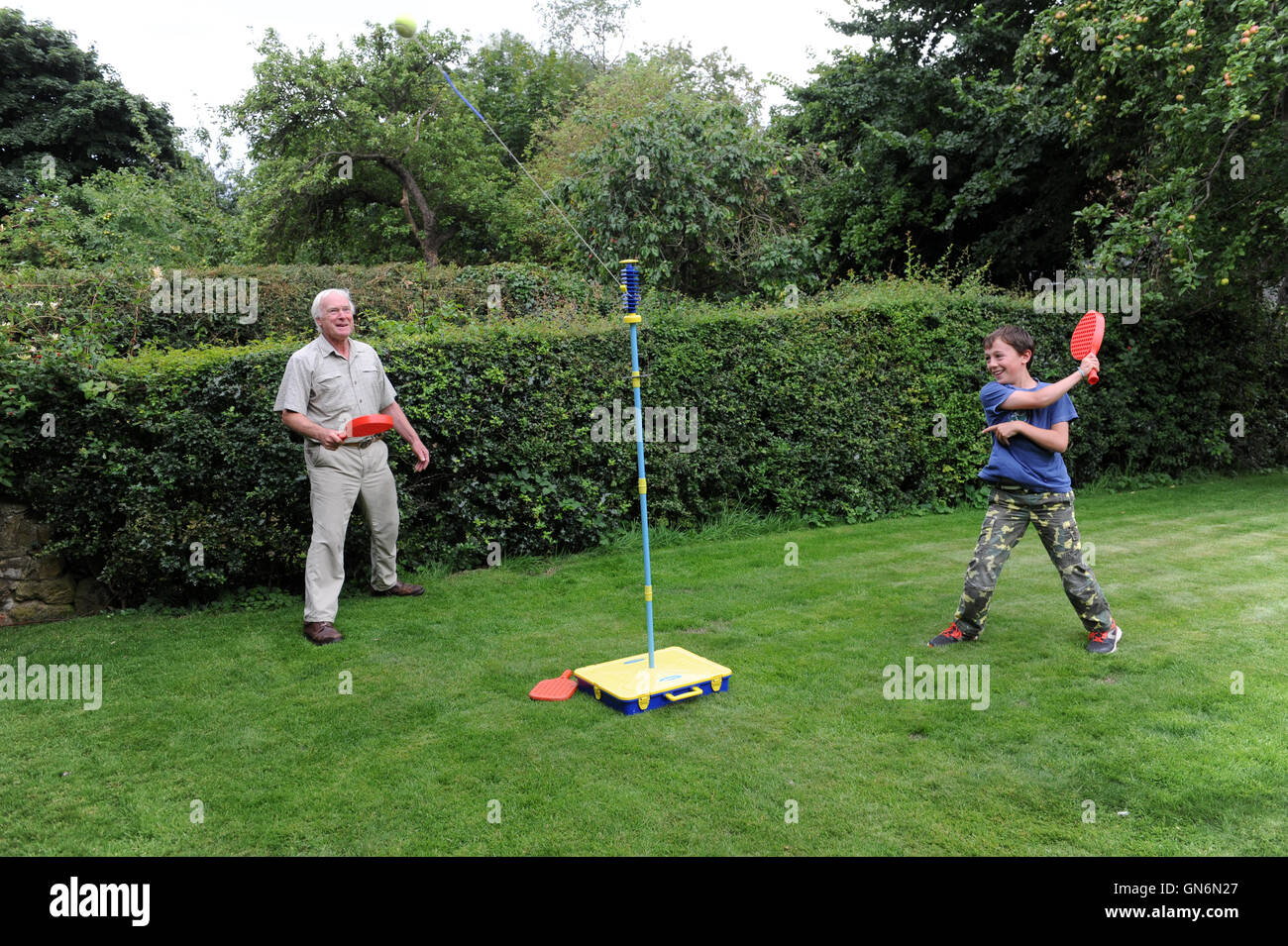 Grandfather playing Swingball with his Grandson in the garden Stock ...