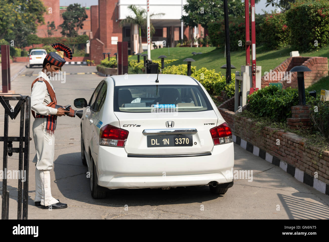 A hotel security guard dressed in Indian style uniform inspects a car ...