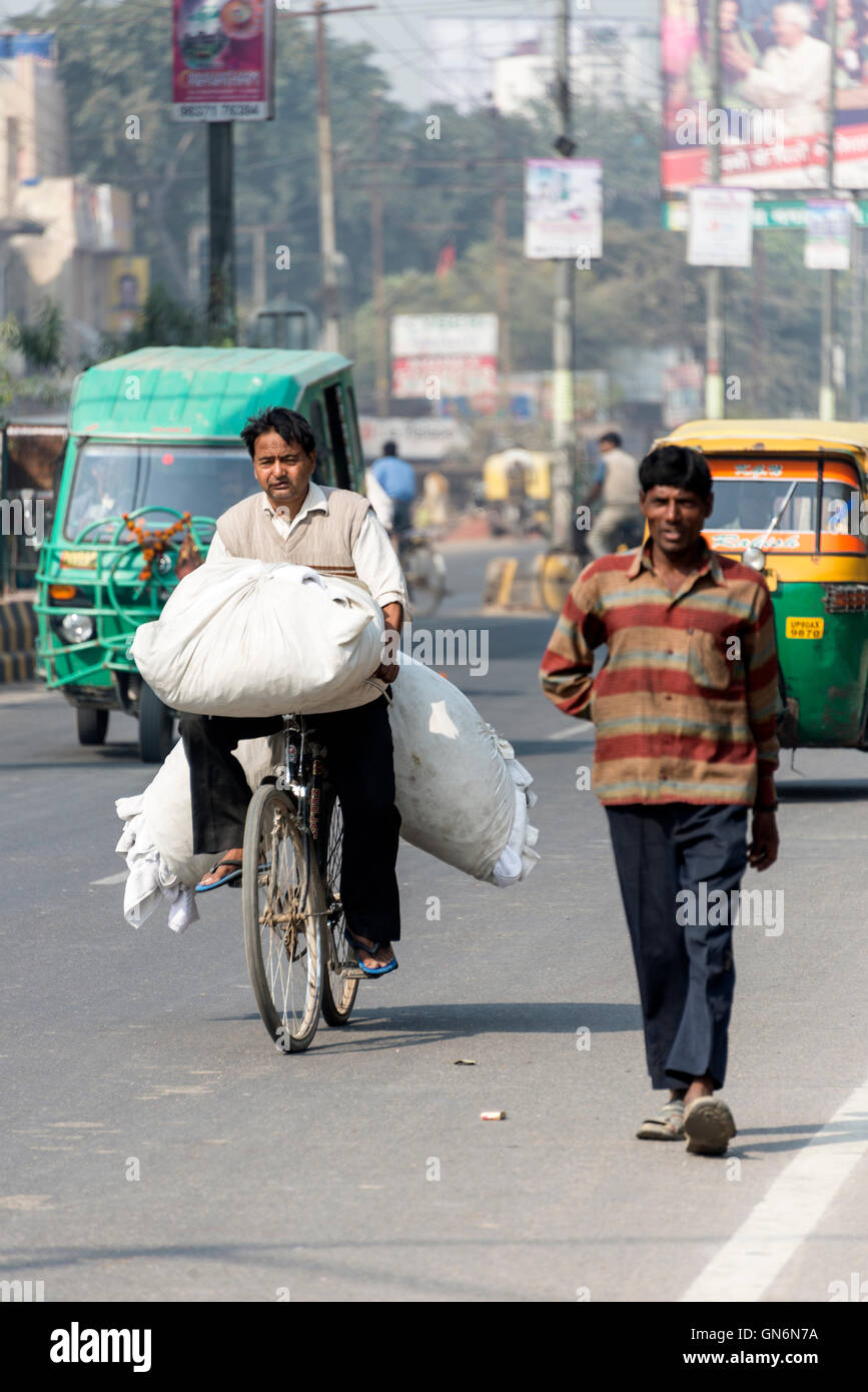 A laundry employee riding his bicycle loaded with laundry on a busy ...