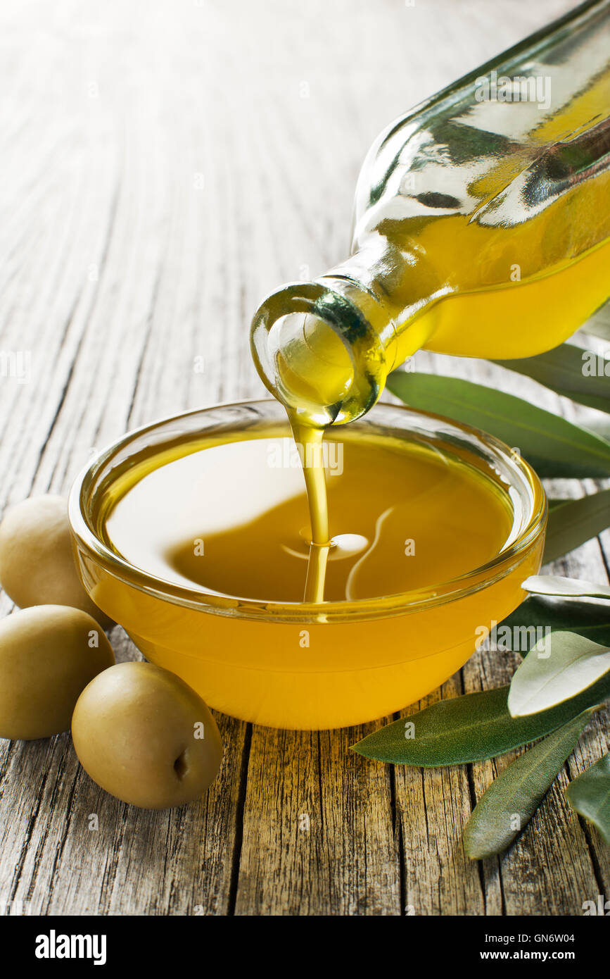 Bottle pouring virgin olive oil in a bowl close up Stock Photo - Alamy