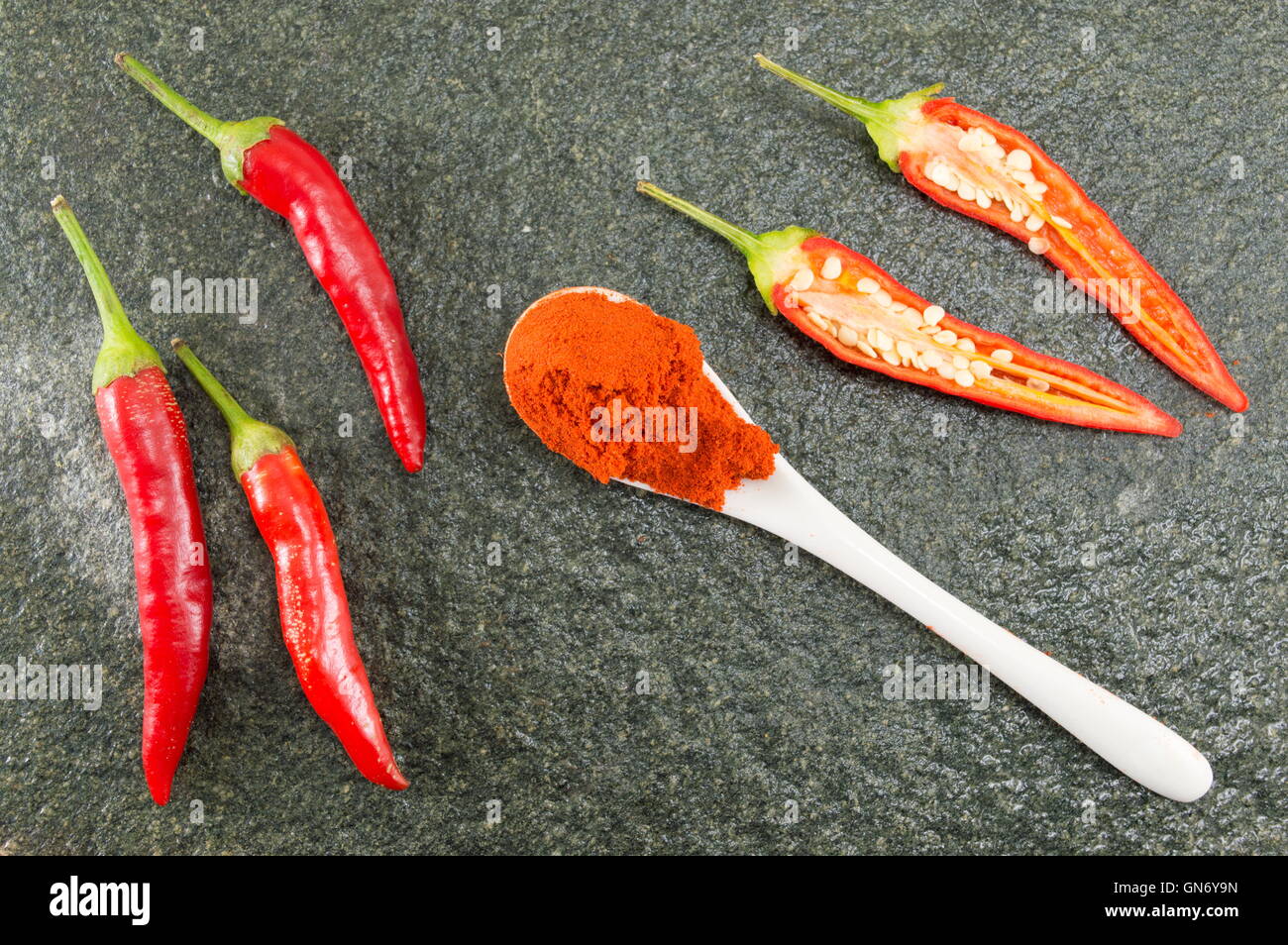 Red hot raw and grounded peppers on stone background Stock Photo - Alamy