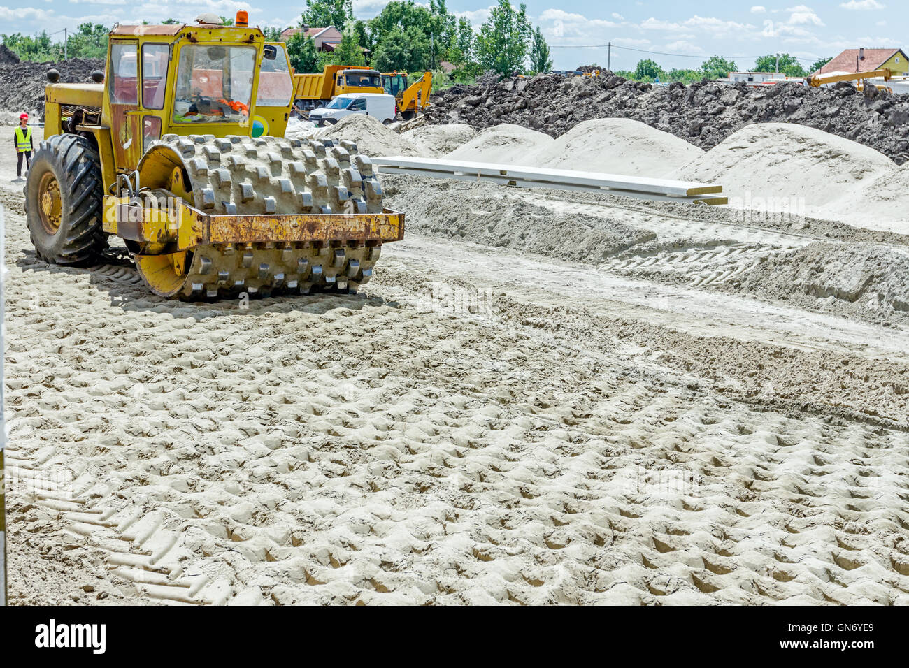 Construction worker is driving huge road roller with spikes and ...