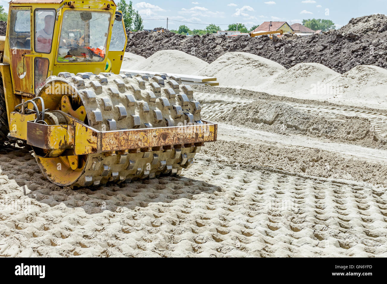 Construction worker is driving huge road roller with spikes and ...
