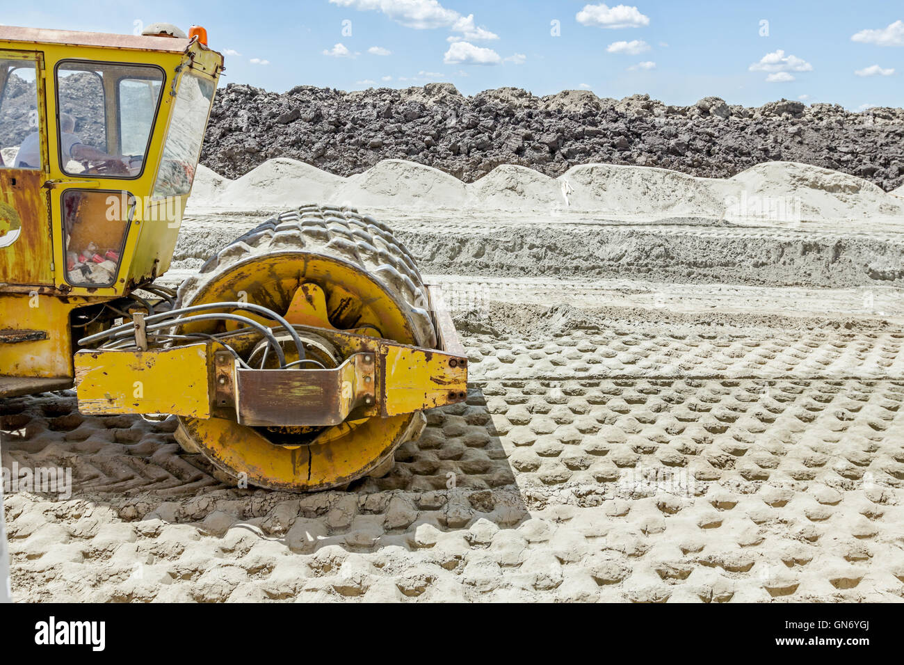 Construction worker is driving huge road roller with spikes and ...