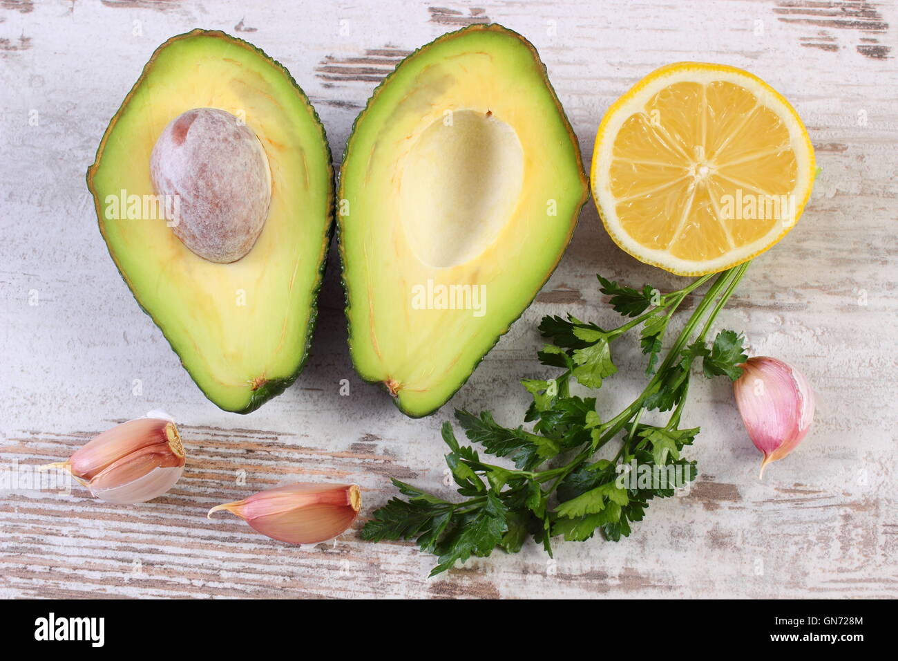 Portion of avocado, clove garlic, lemon and parsley, concept of healthy ...