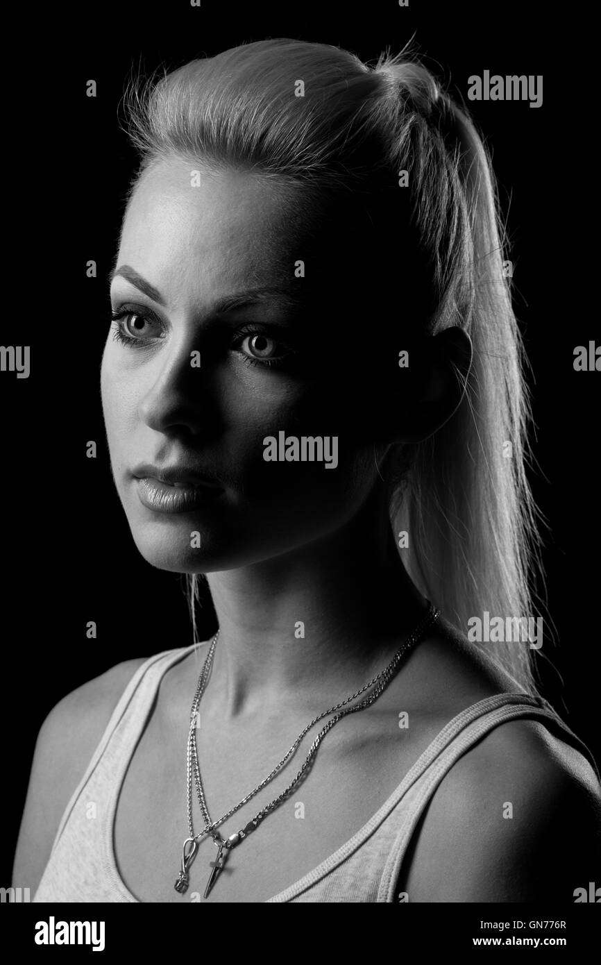 Portrait of beautiful blonde woman in darkness with soft light on her ...