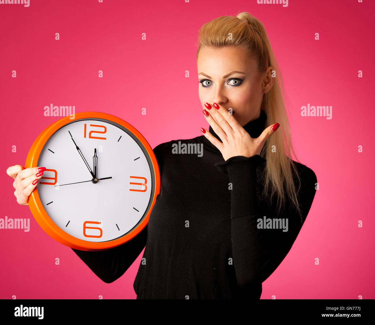 Worried woman with big orange clock gesturing delay, rush, nervous ...