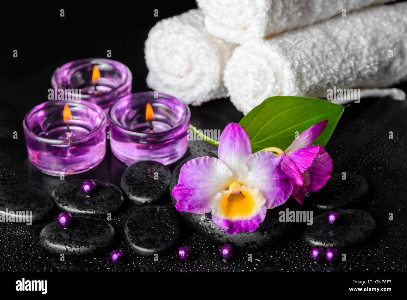 spa still life of purple orchid dendrobium, leaf with dew, towels ...