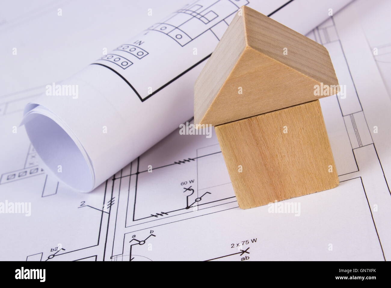 House shape made of wooden blocks and rolls of diagrams lying on ...