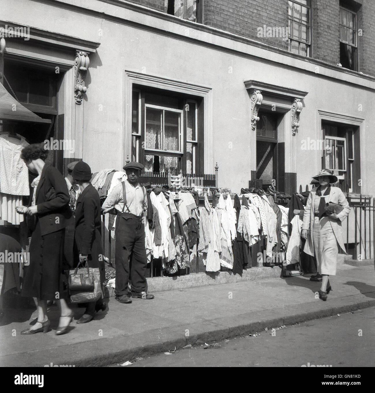 1930s, historical picture, street trader selling clothing hanging on ...