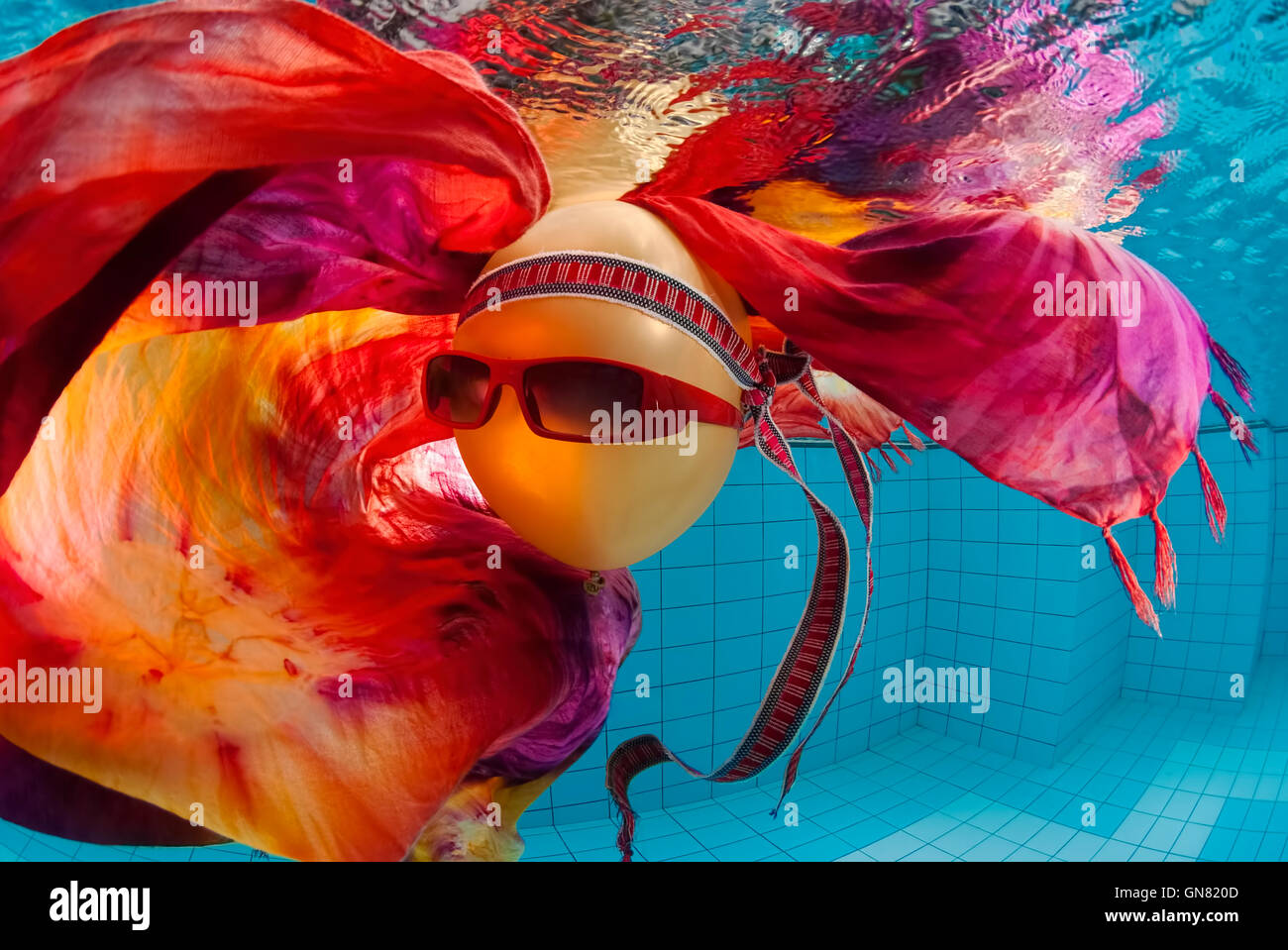 Colorful party balloon with sunglasses underwater in a swimming pool ...