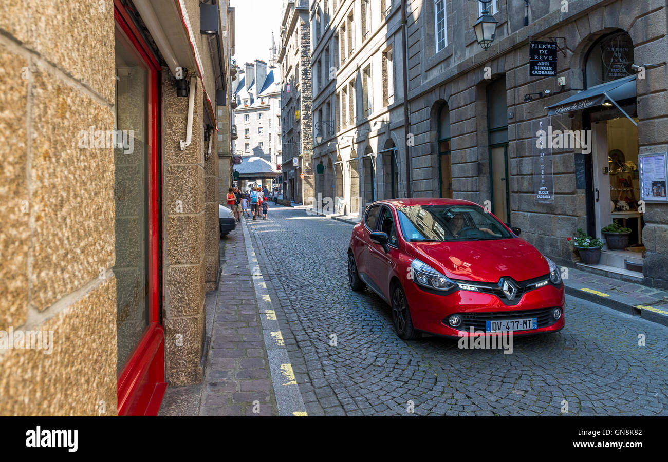 Red Renault car driving slowly down the narrow cobble street in the ...