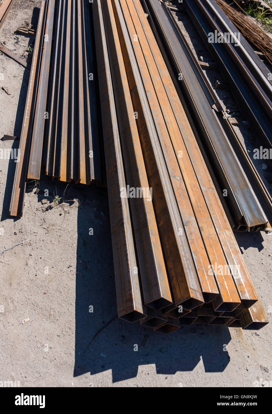 Metal rolling. Long steel square tubes folded on the ground Stock Photo ...