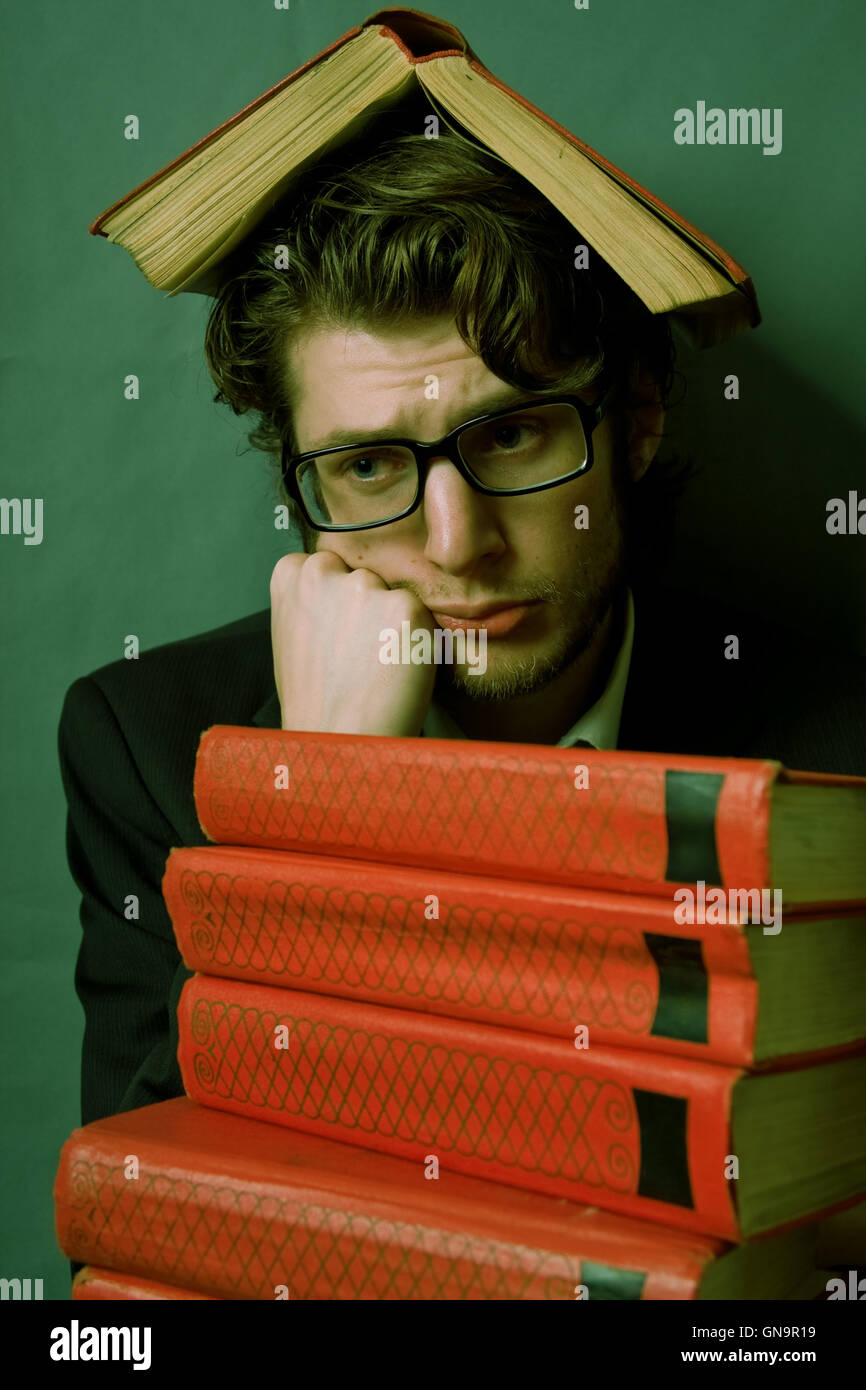 sad young man with a stack of red books Stock Photo - Alamy