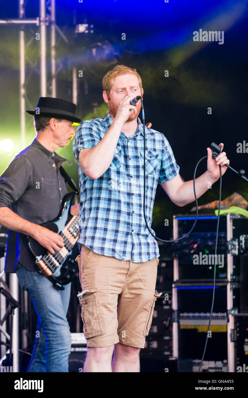 Caucasian man, Paul Cook, sanding on stage singing into microphone ...