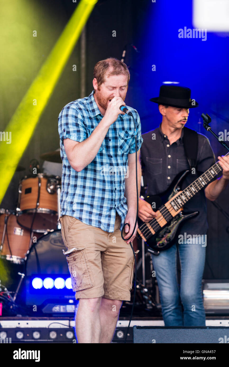 Caucasian man, Paul Cook, sanding on stage singing into microphone ...