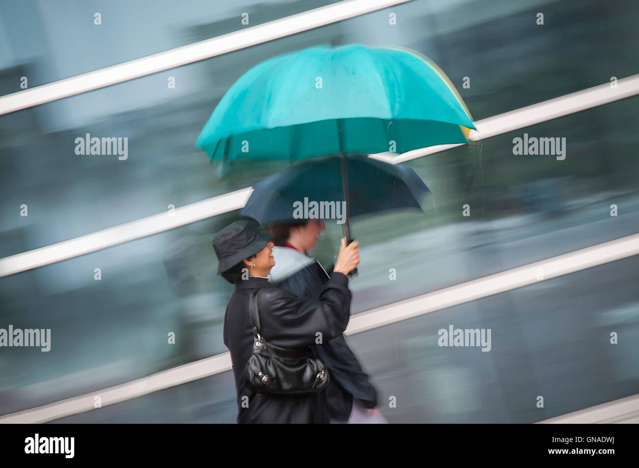 Two women under umbrella in rain Stock Photo - Alamy