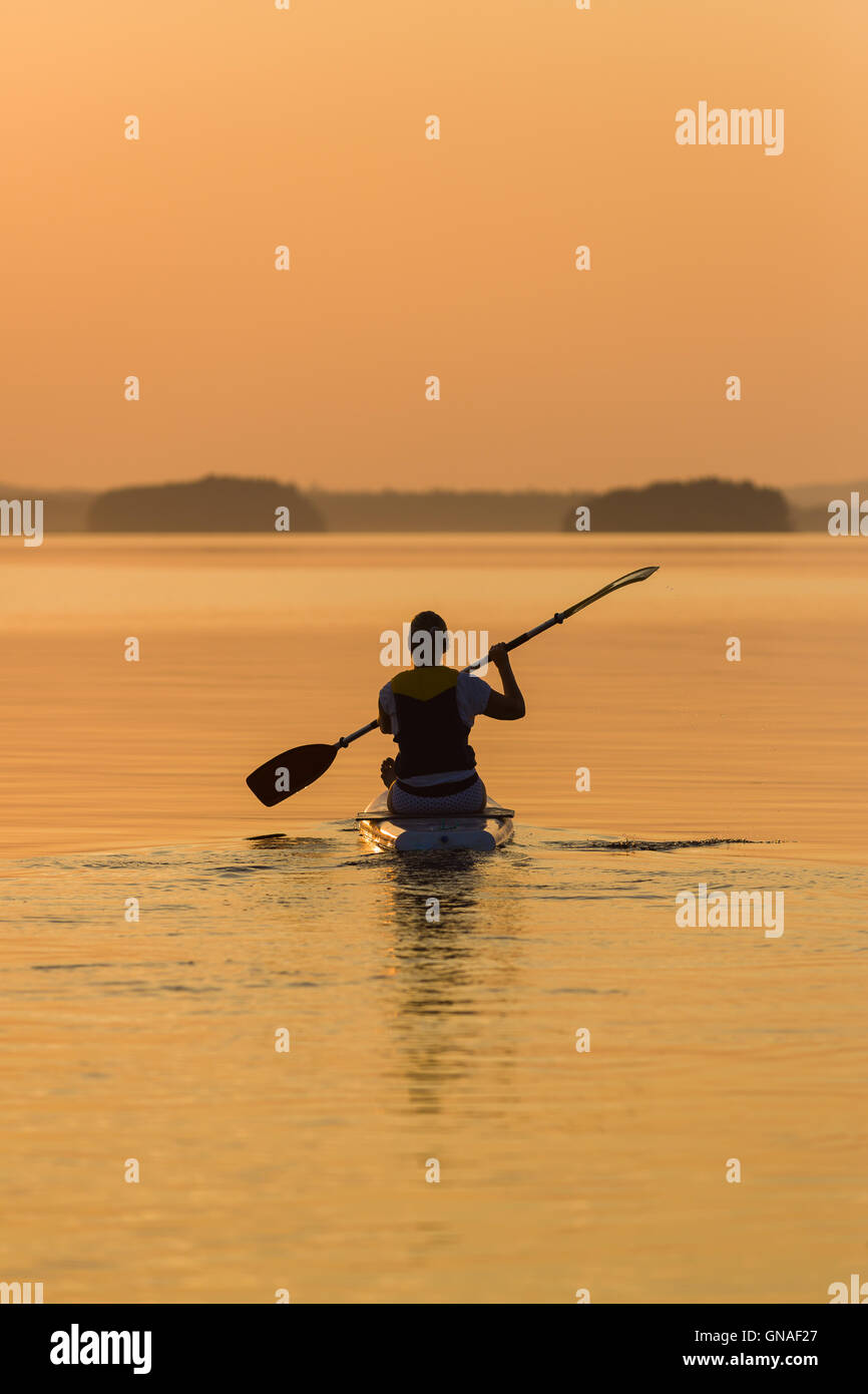 Paddle-boarding on lake during sunset Stock Photo - Alamy