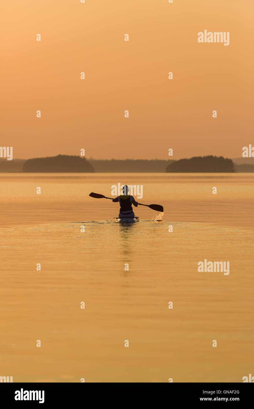 Paddle-boarding on lake during sunset Stock Photo - Alamy
