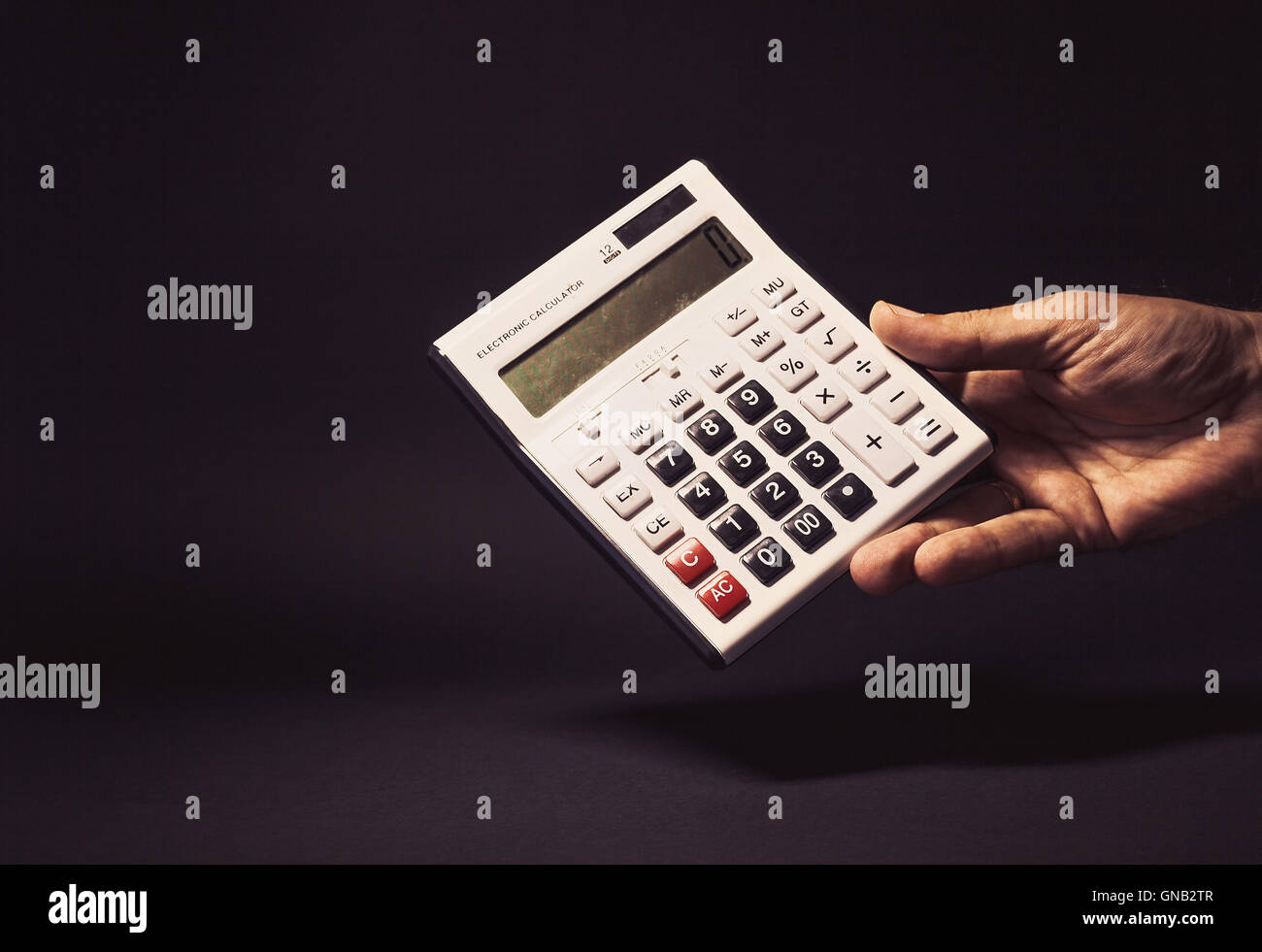 Conceptual composition, man's hand holding an old electronic calculator ...