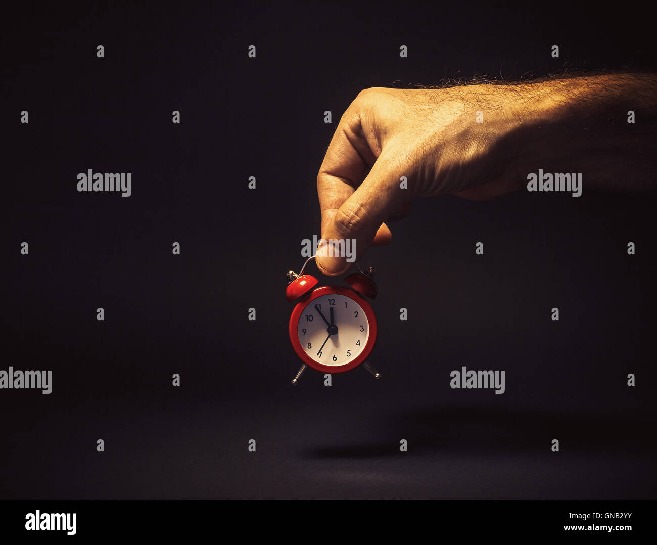 Conceptual composition, man's hand holding a red souvenir clock, time ...