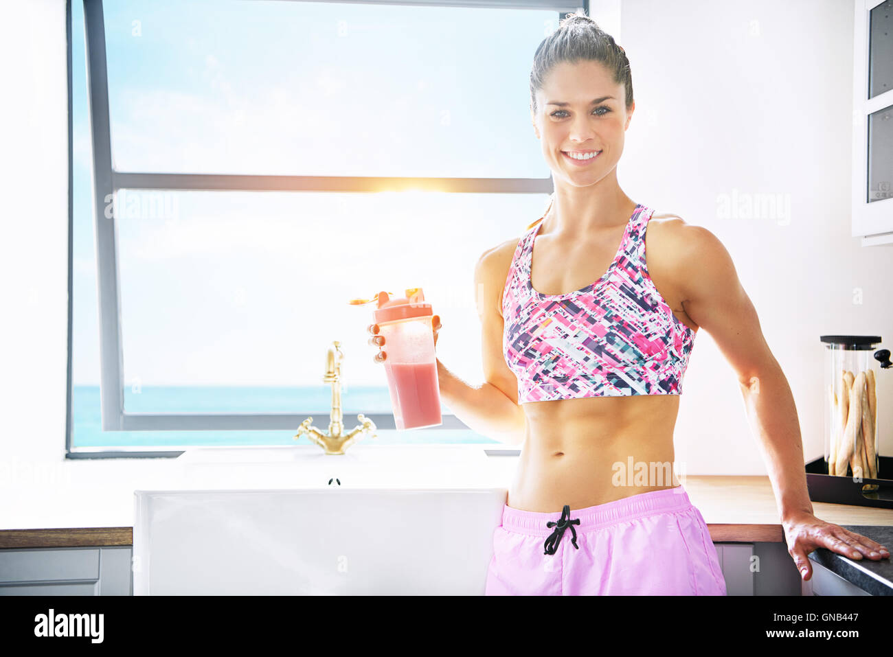 Pretty vivacious shapely fit young woman drinking fruit juice in a ...