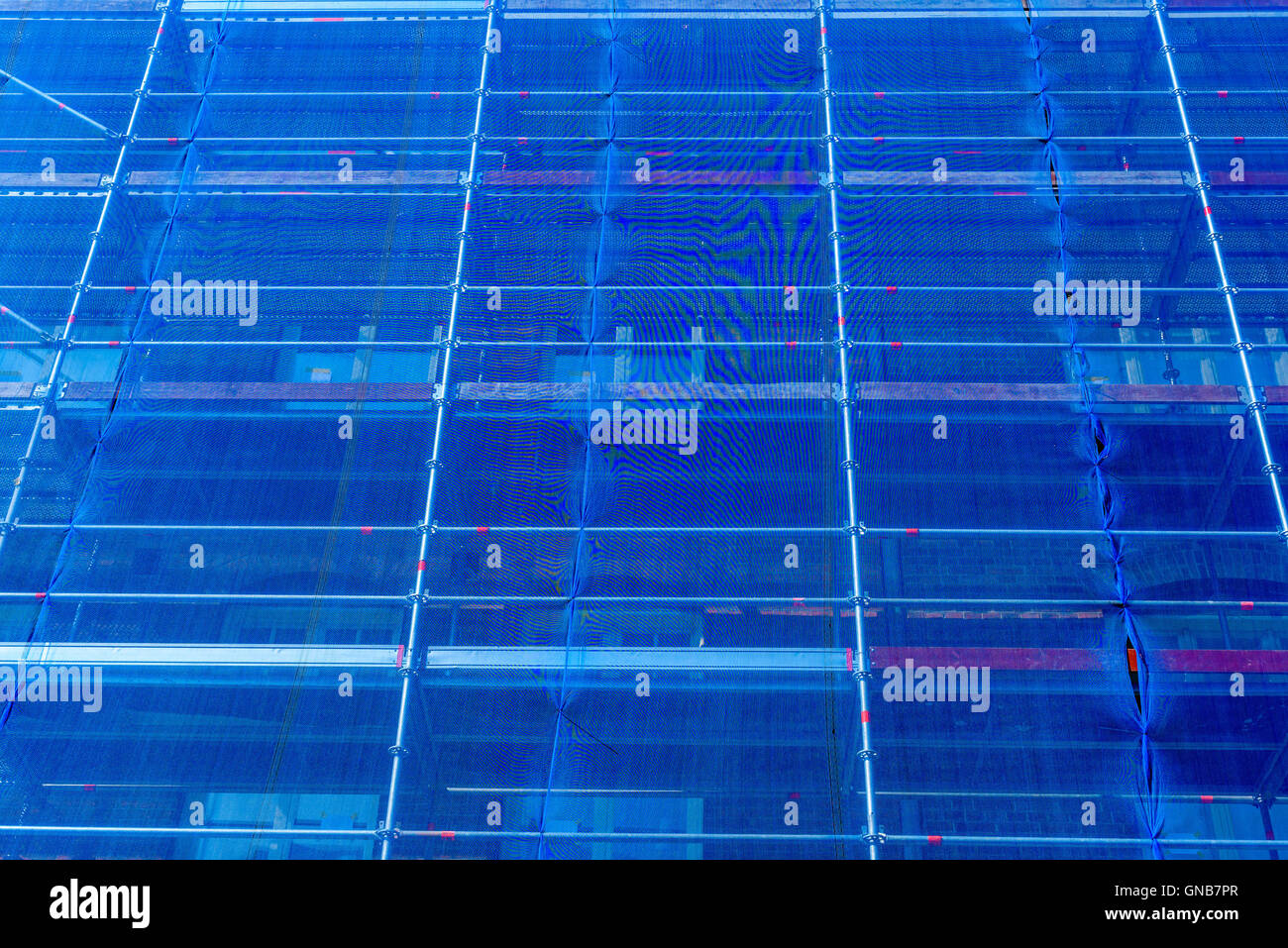 Blue netting covering a construction site. Parts of scaffoldings ...