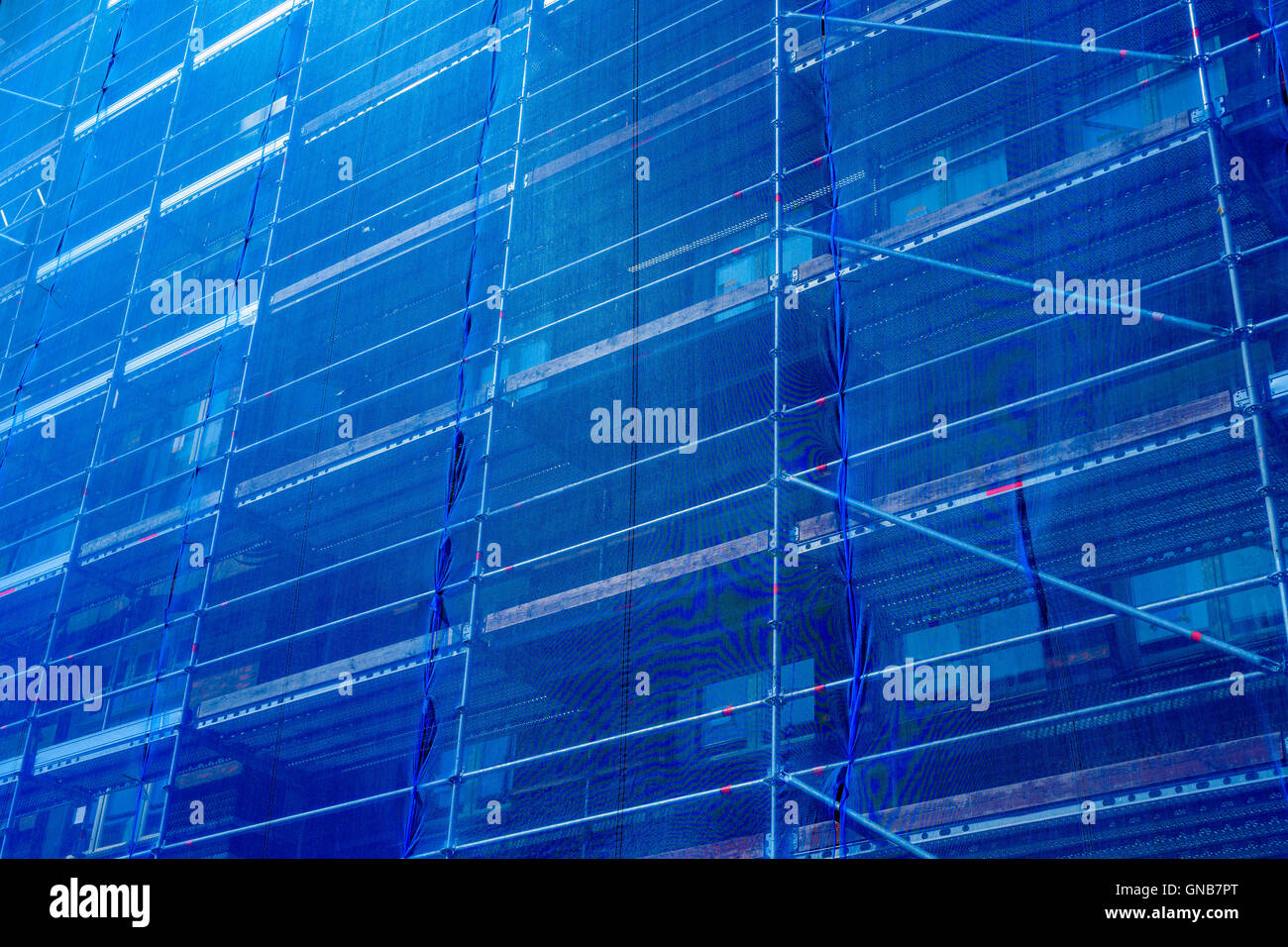 Blue netting covering a construction site. Parts of scaffoldings ...