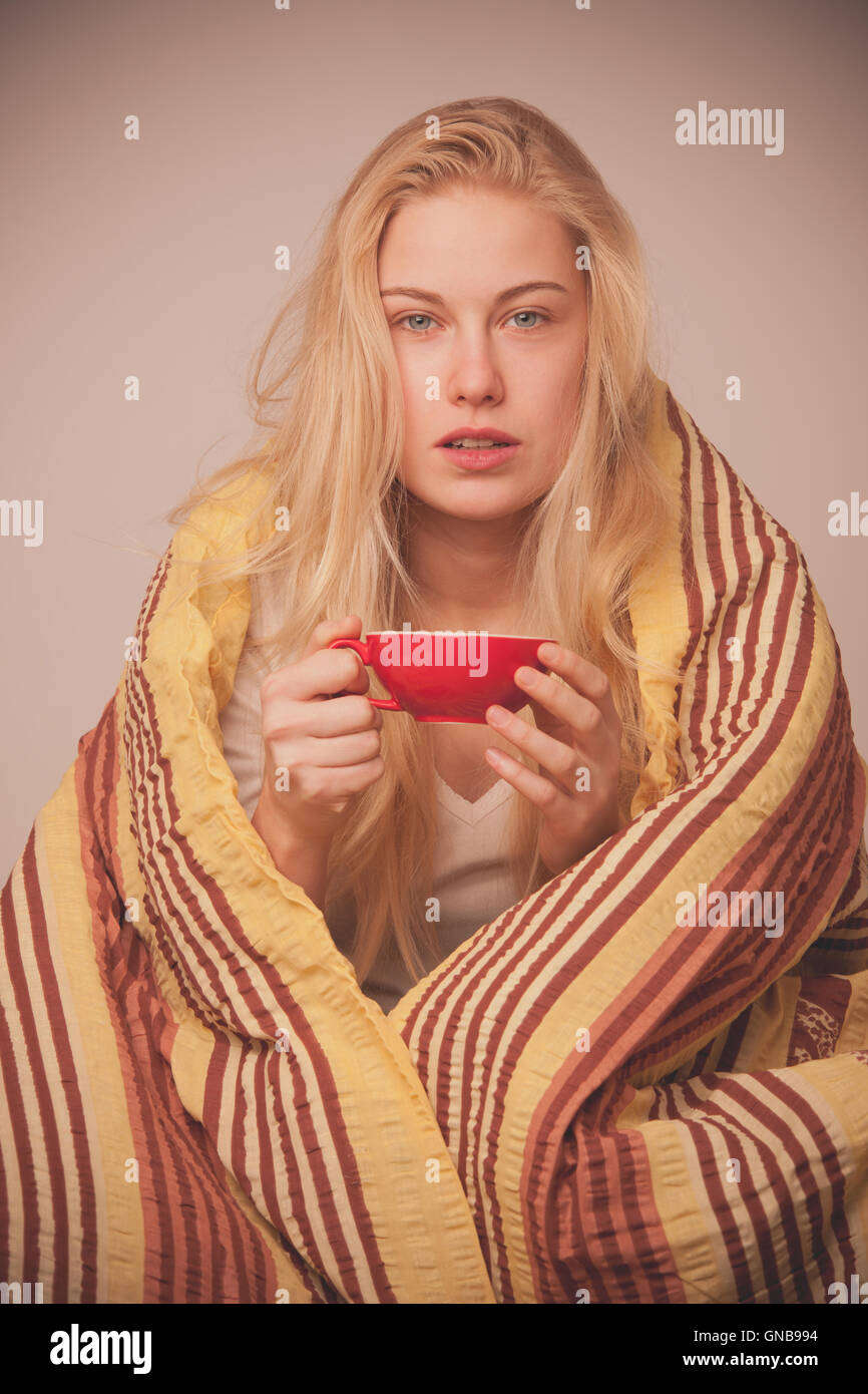 Sick woman sitting on bad wrapped in a blanket feeling ill, has flu and ...