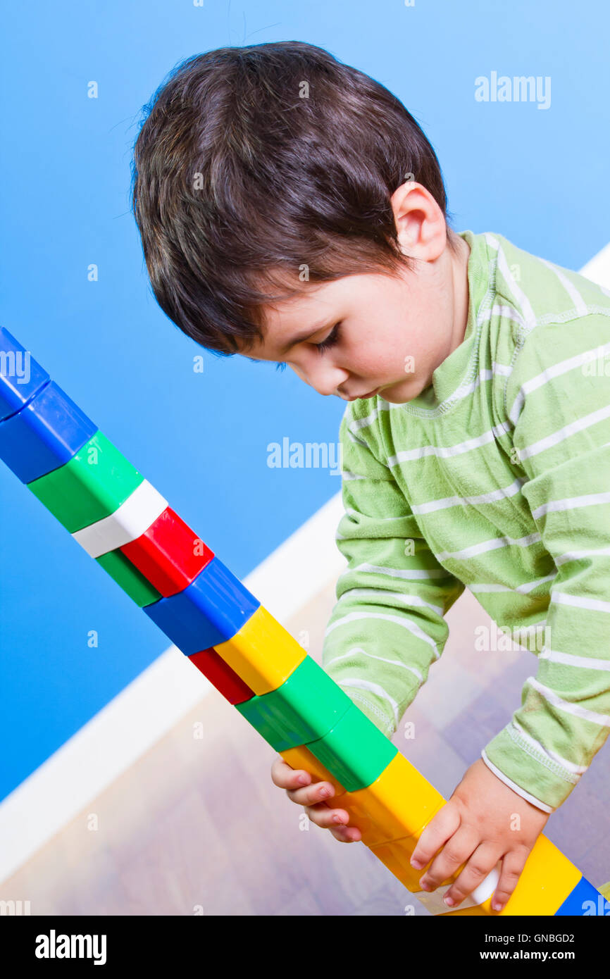 A smiling little boy is building a toy block. Wooden room Stock Photo ...