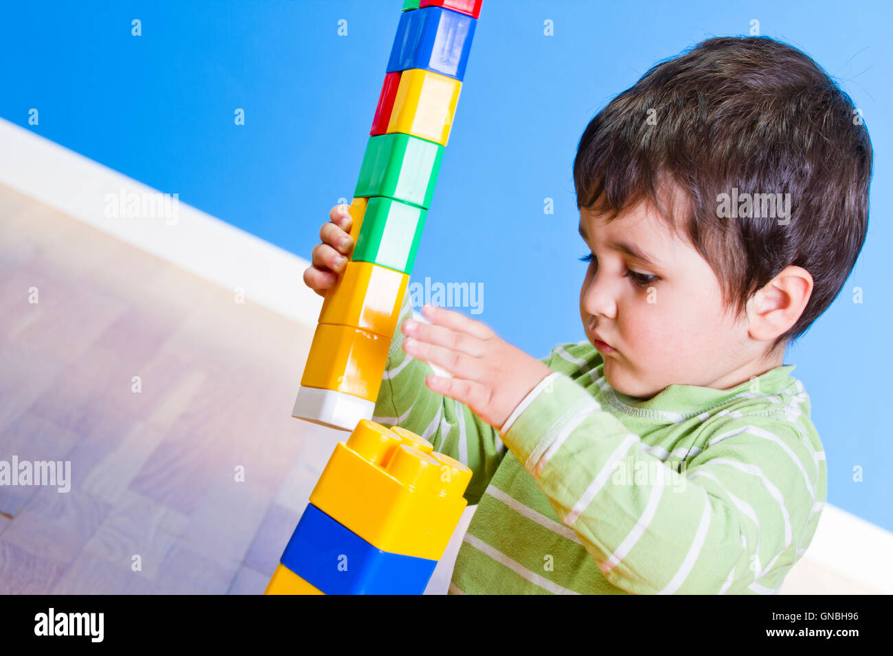 A smiling little boy is building a toy block. Wooden room Stock Photo ...