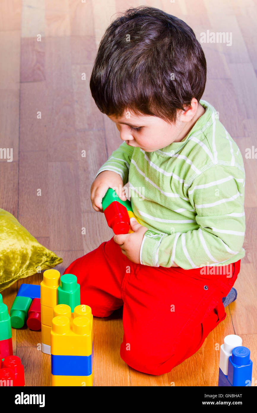 A happy little boy is building a colorful toy block tower Stock Photo ...