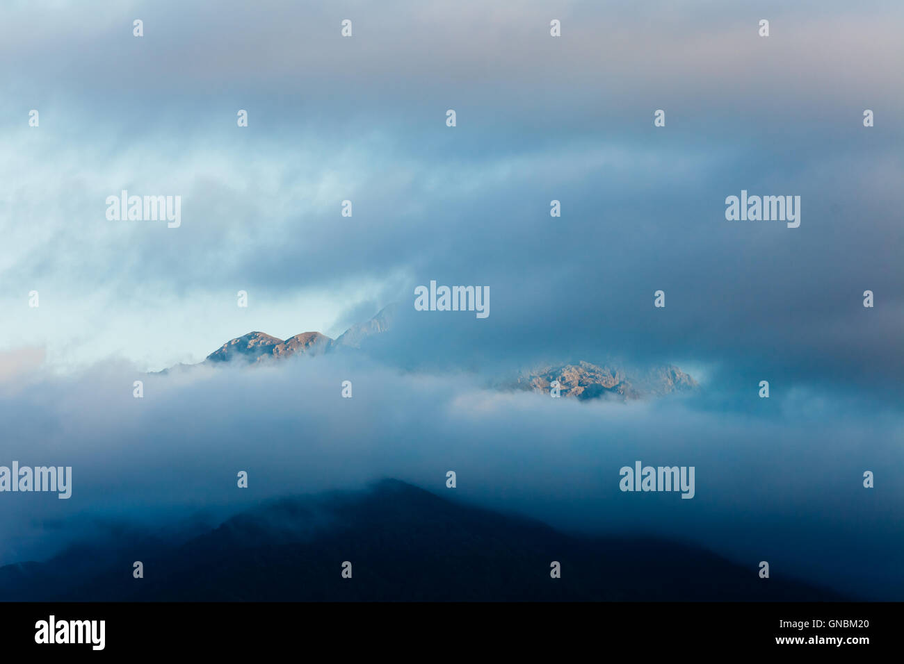 Dark sunset clouds over high rugged mountain peaks Stock Photo - Alamy