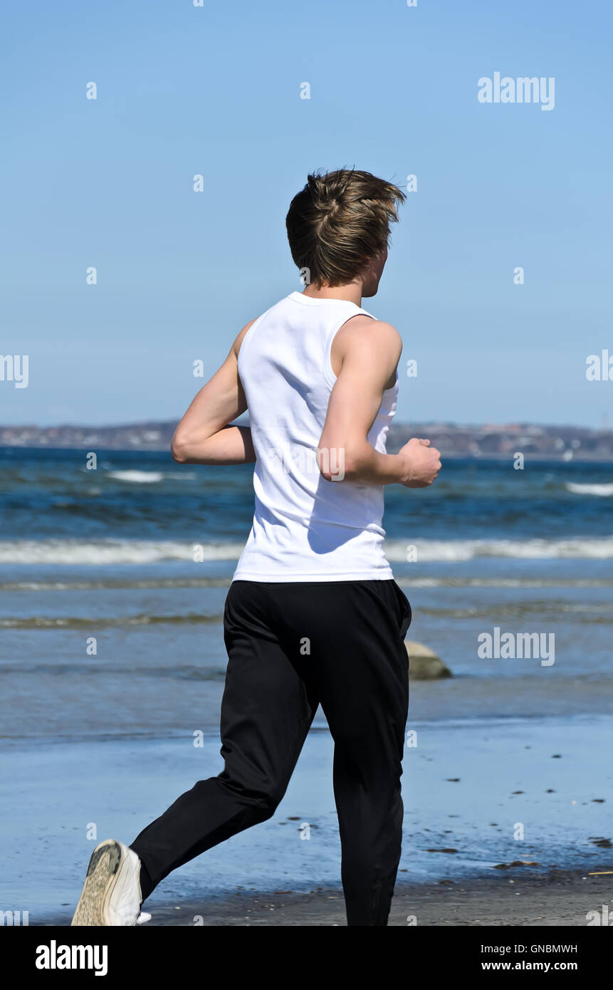 Athletic young male running on the beach. From the back Stock Photo - Alamy