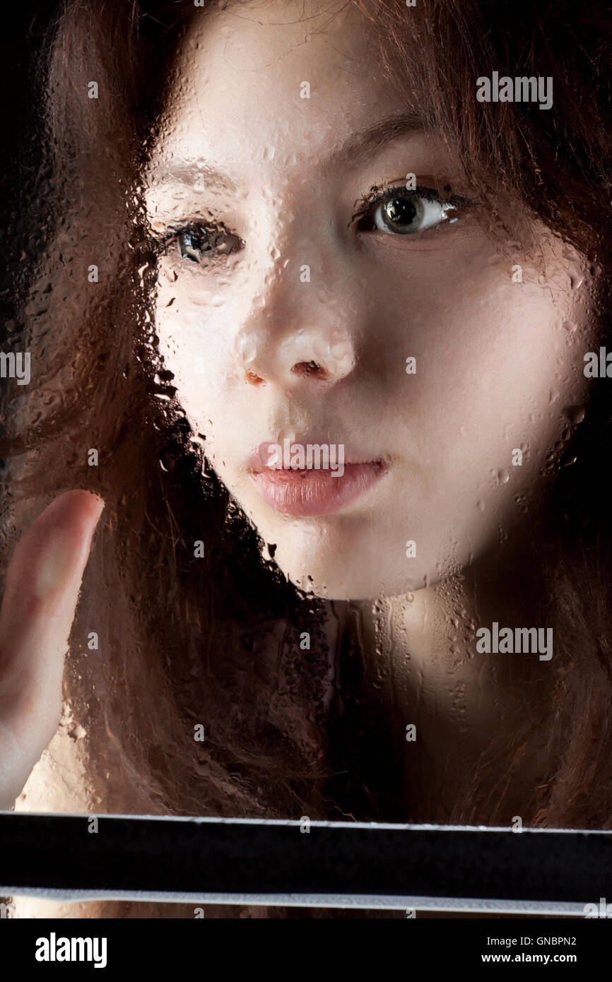 young sad woman behind wet window Stock Photo - Alamy