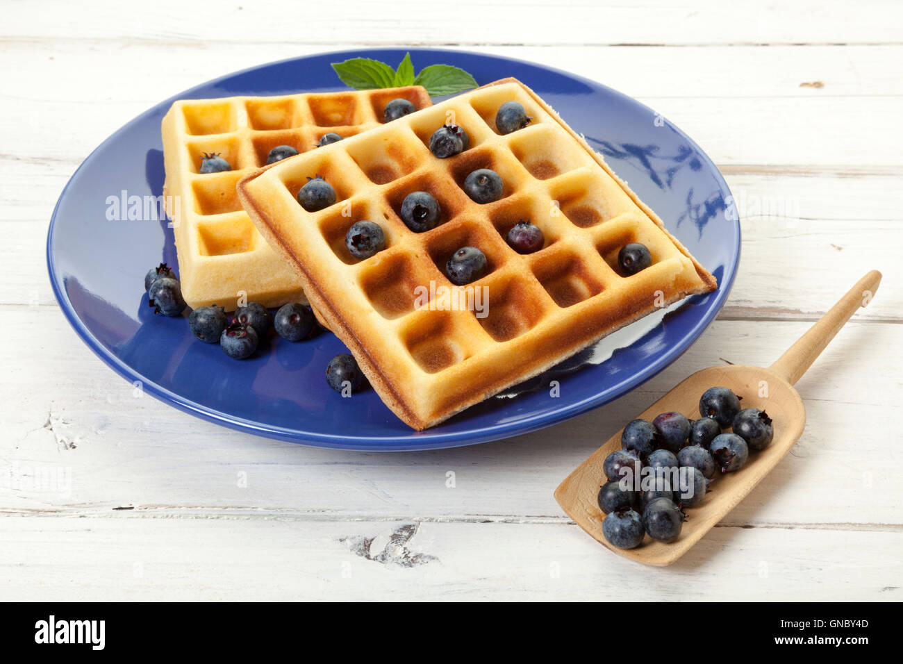 Belgian waffles with blueberries on blue plate, on rustic wooden table ...