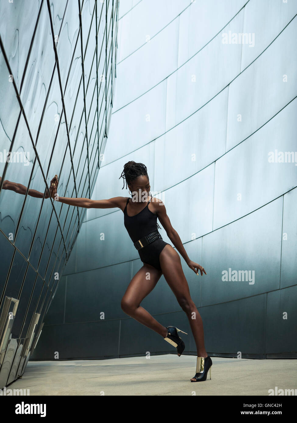 Woman in Black Unitard and High Heel Shoes Leaning Against Modern ...