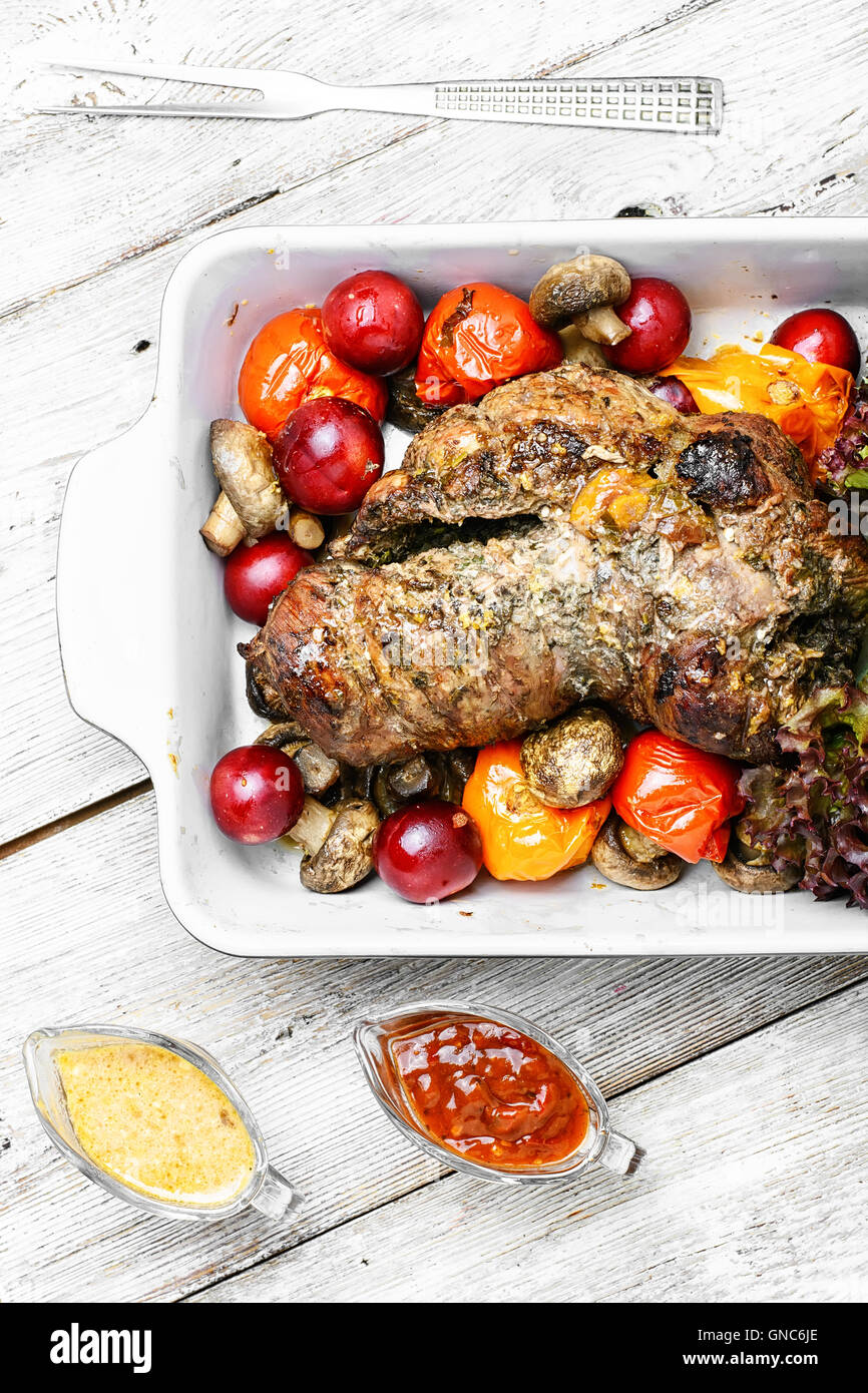 Meat knuckle of beef in the baking dish with tomatoes and plum sauce ...