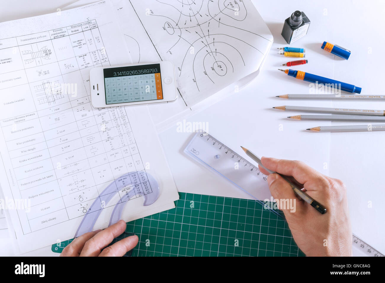 Overhead view on the papers and hands drawing map or doing homework ...
