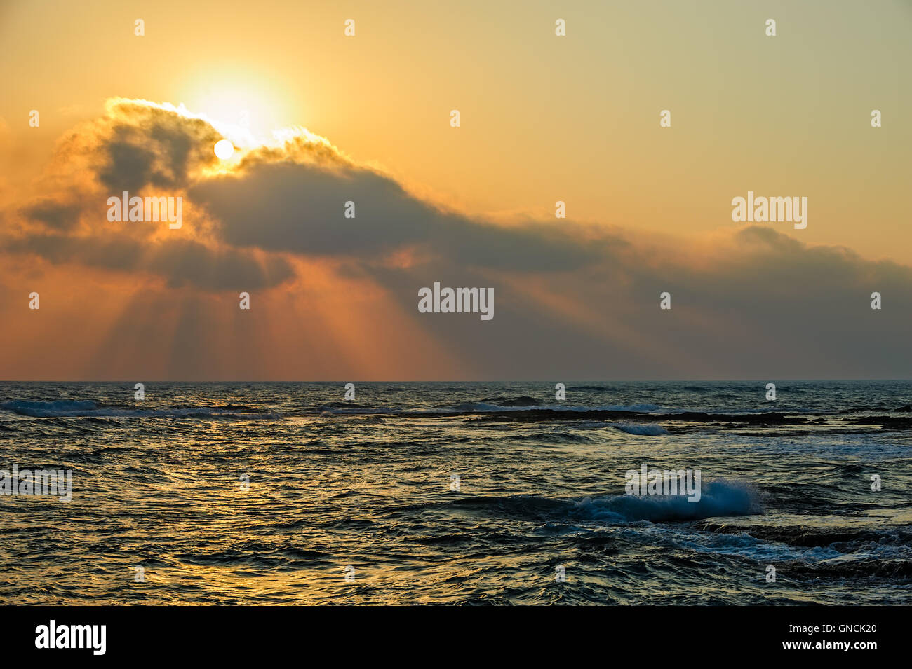 Sunset over sea with sun beams through clouds Stock Photo - Alamy