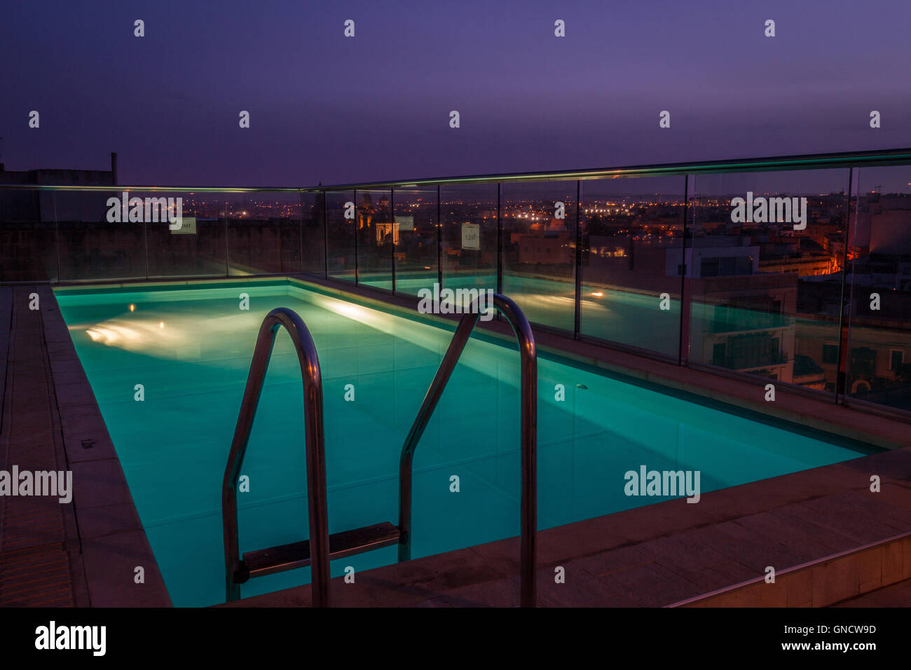 lights shining in blue pool on rooftop with evening night sky over city ...