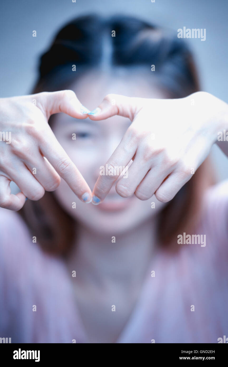 asia smiling cheerful young woman making heart sign with hands ...