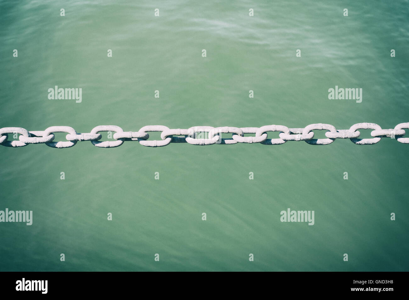 Metal chain across the frame green water in background Stock Photo - Alamy