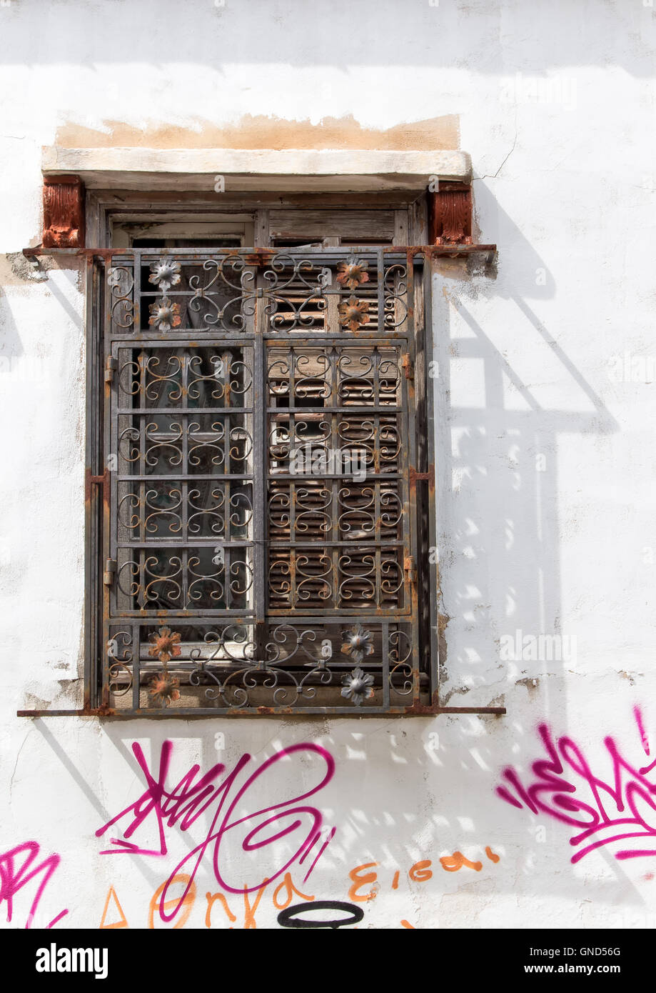 Old destroyed window with ornate lattice. White facade of the house ...
